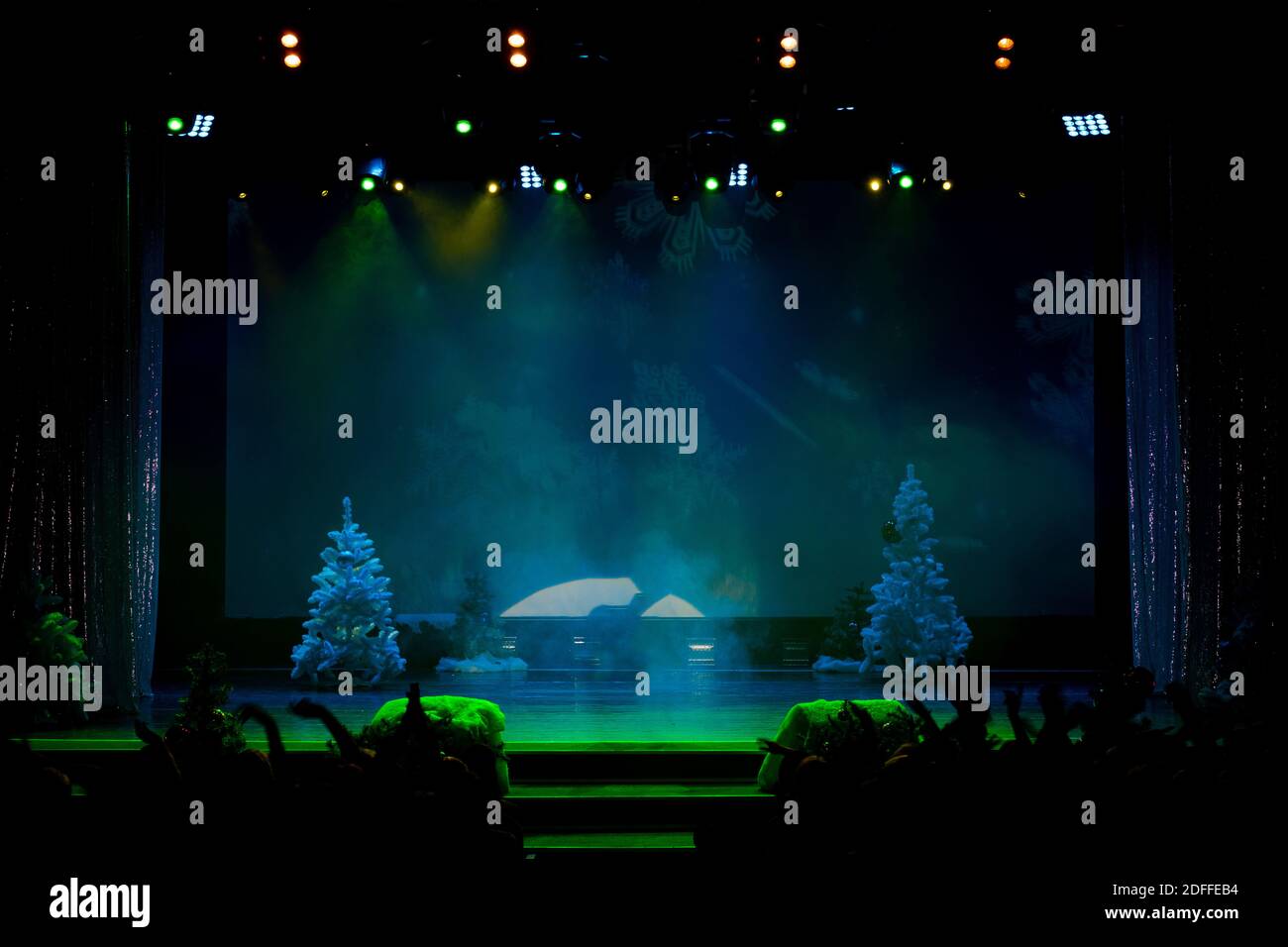 A theater stage with a curtain illuminated by stage light and smoke ...