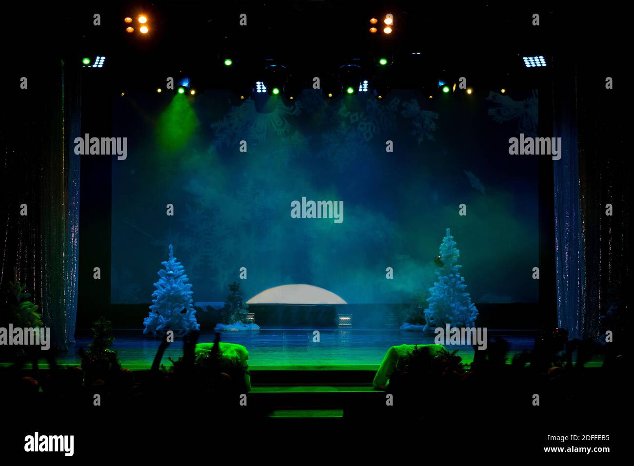 A theater stage with a curtain illuminated by stage light and smoke ...