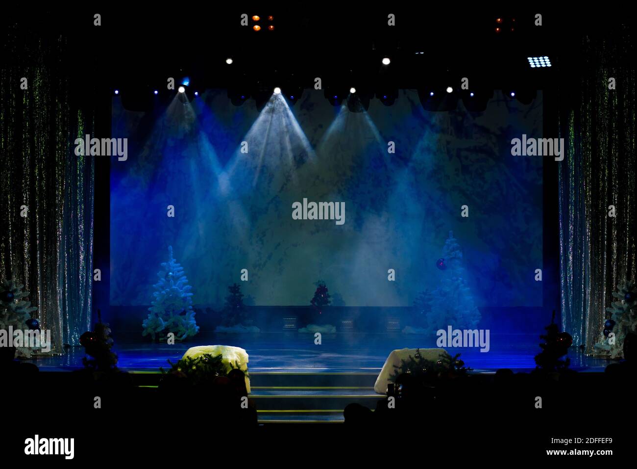 A theater stage with a curtain illuminated by stage light and smoke ...