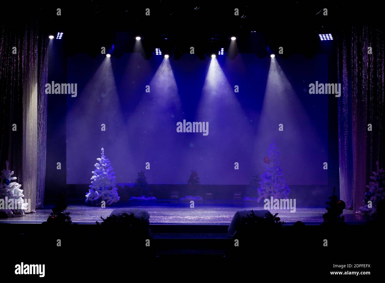 A theater stage with a curtain illuminated by stage light and smoke ...