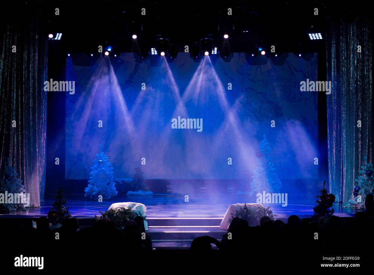 A theater stage with a curtain illuminated by stage light and smoke ...