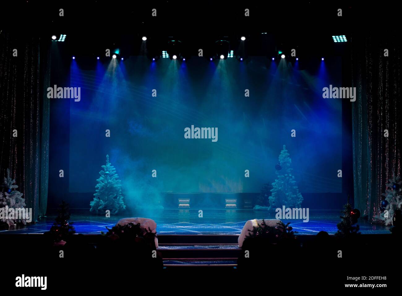 A theater stage with a curtain illuminated by stage light and smoke ...