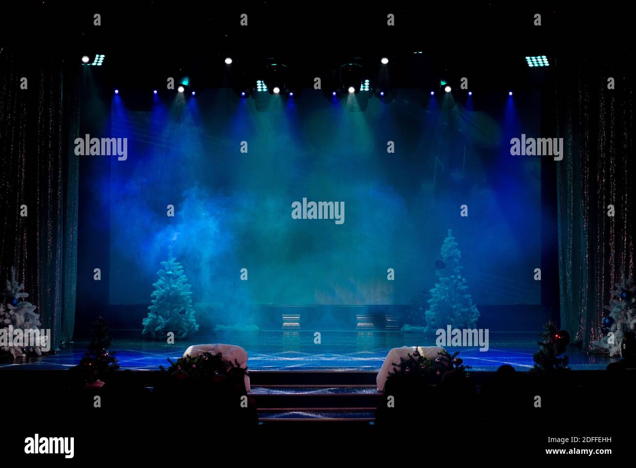 A theater stage with a curtain illuminated by stage light and smoke ...