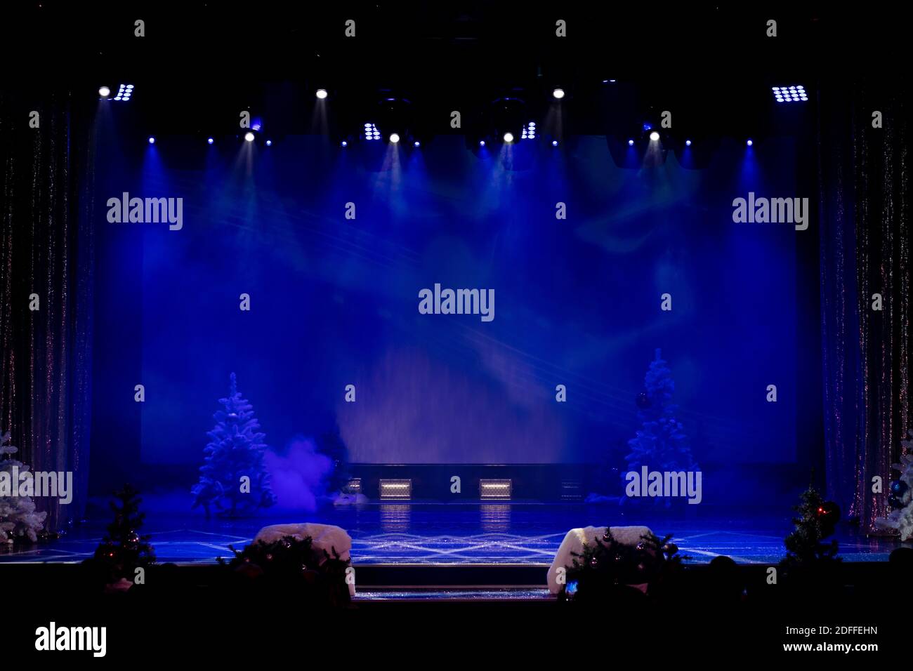 A theater stage with a curtain illuminated by stage light and smoke ...