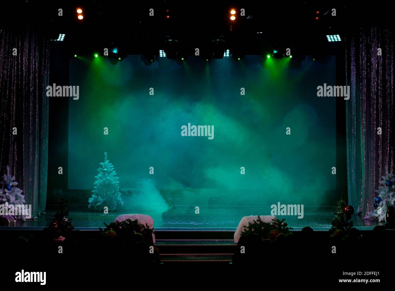 A theater stage with a curtain illuminated by stage light and smoke ...