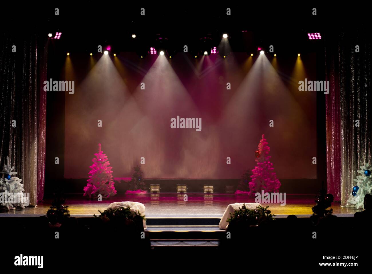 A theater stage with a curtain illuminated by stage light and smoke ...