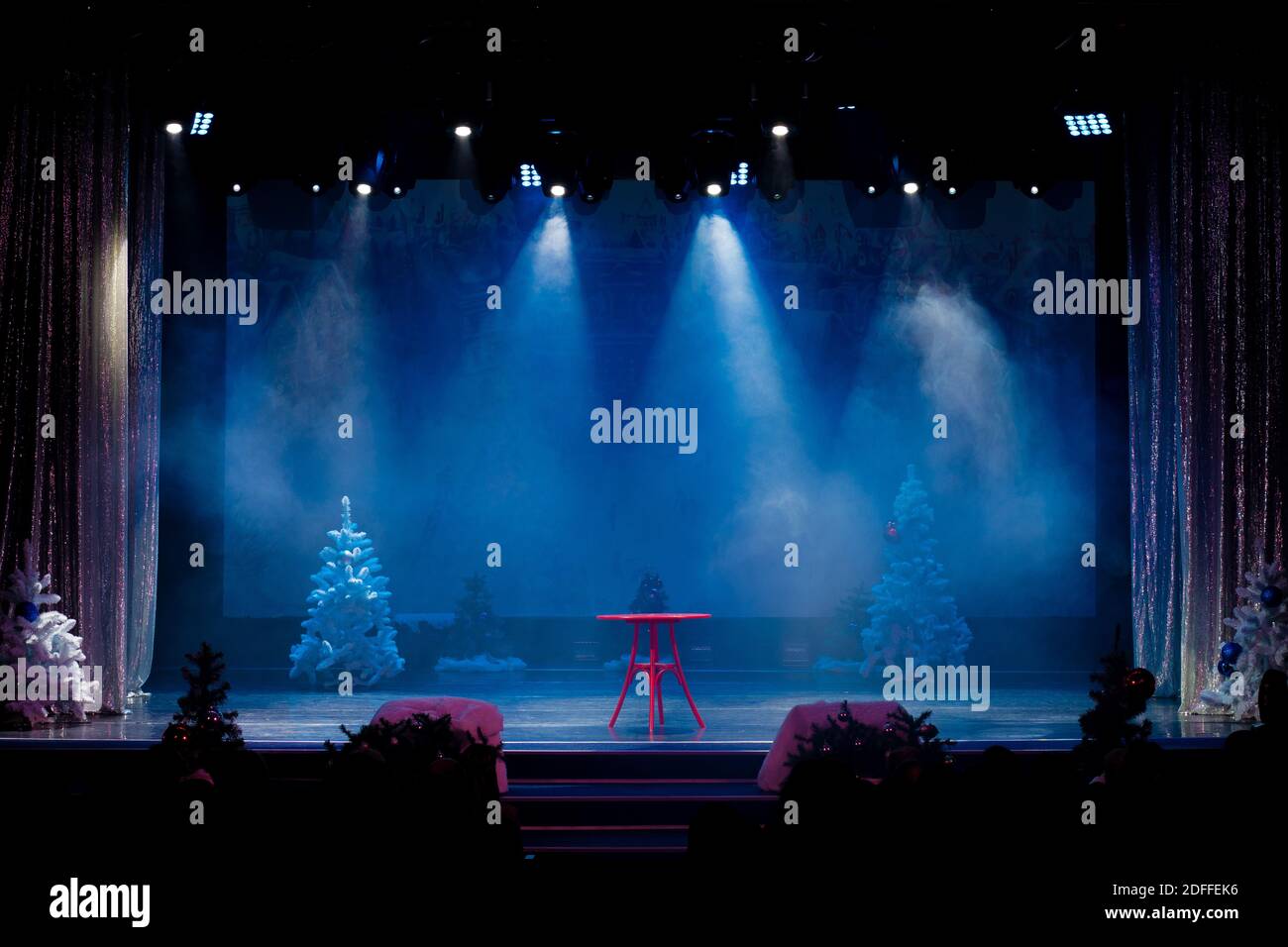 A theater stage with a curtain illuminated by stage light and smoke ...