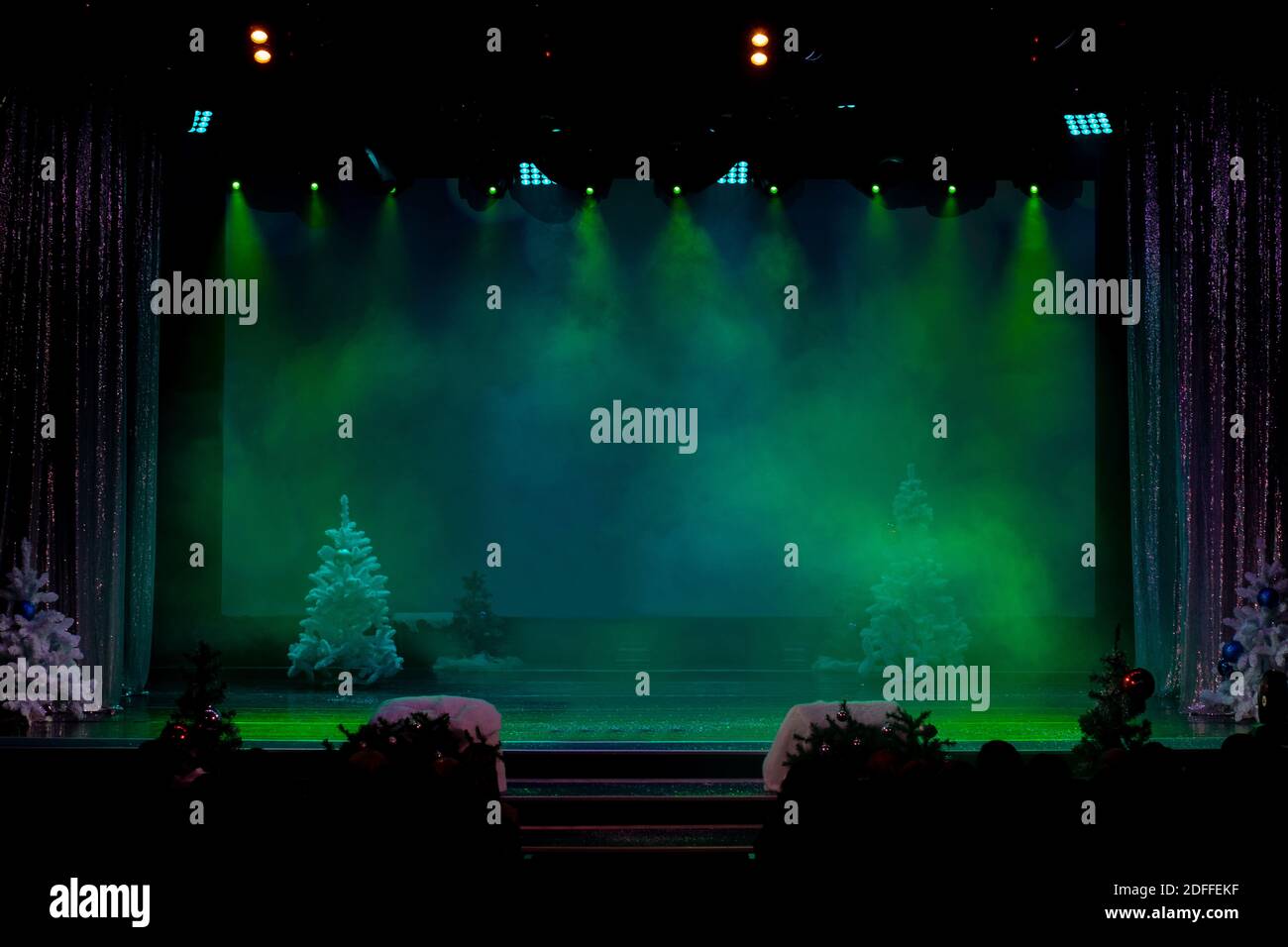 A theater stage with a curtain illuminated by stage light and smoke ...