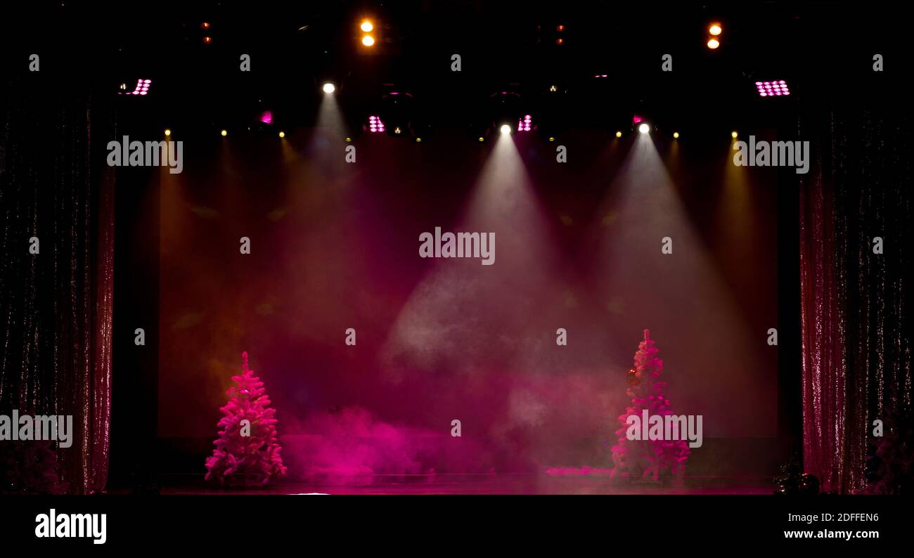 A theater stage with a curtain illuminated by stage light and smoke ...