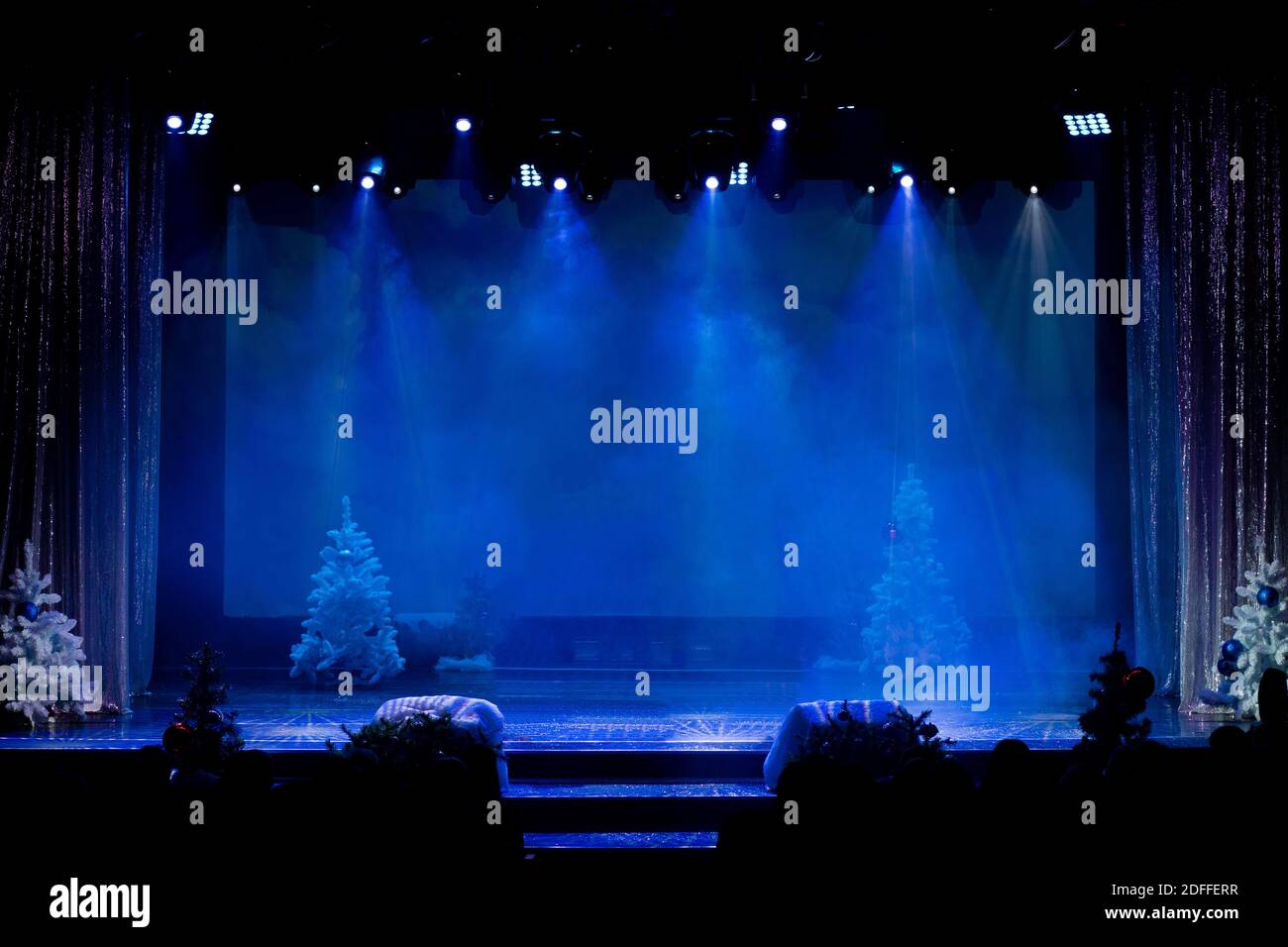 A theater stage with a curtain illuminated by stage light and smoke ...