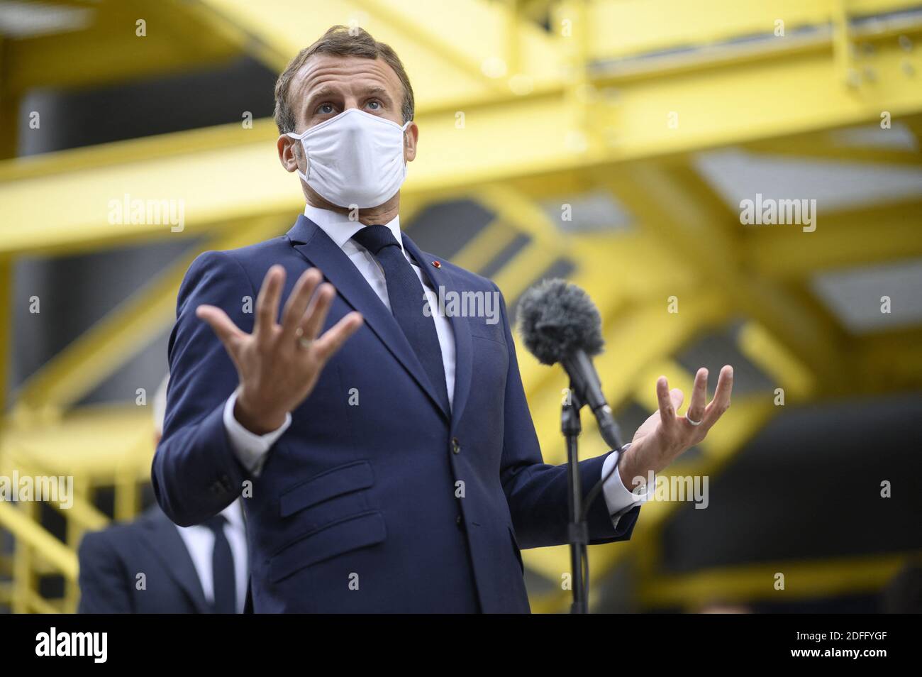 French President Emmanuel Macron, wearing a protective face mask ...