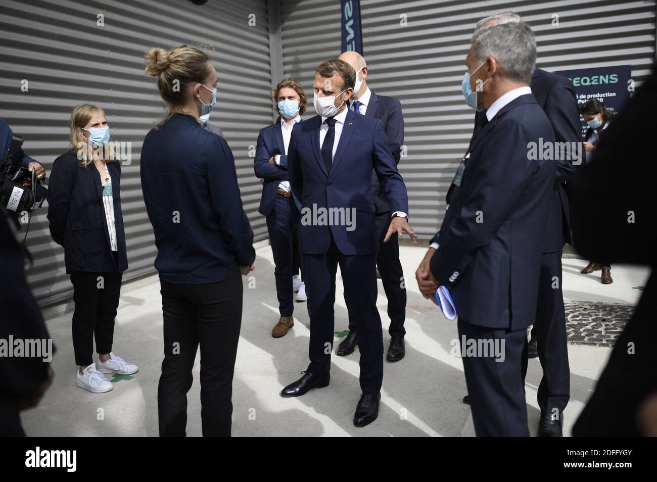 French President Emmanuel Macron, wearing a protective face mask, talks ...