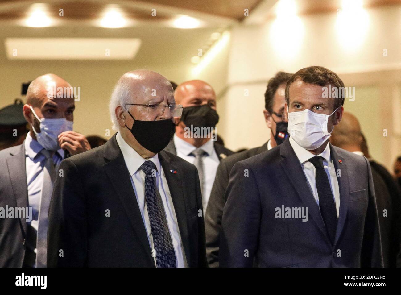 French President Emmanuel Macron, wearing a face mask, speaks to the ...