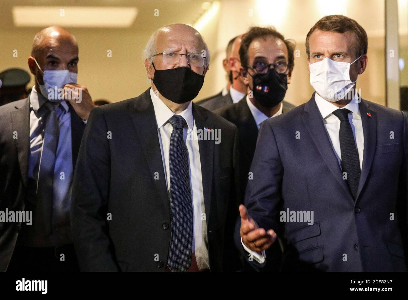 French President Emmanuel Macron, wearing a face mask, speaks to the ...