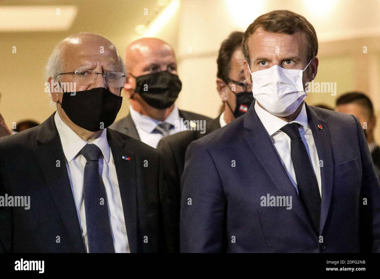 French President Emmanuel Macron, wearing a face mask, speaks to the ...