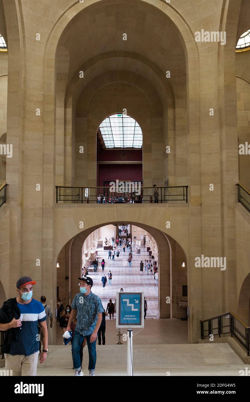 Tourists wearing protective face mask walk in the Denon Wing as they ...