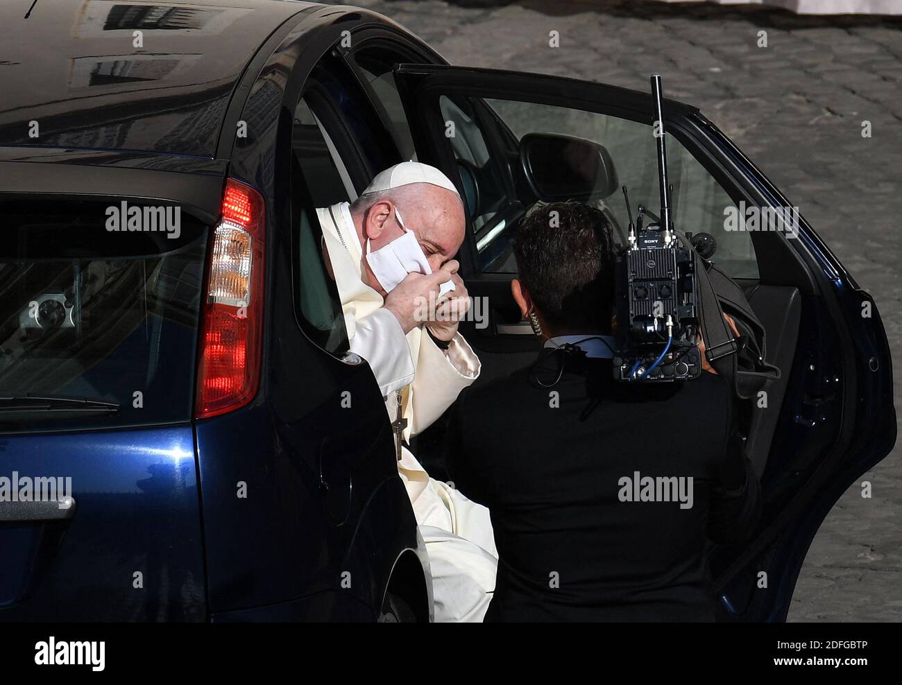 Pope Francis takes off his face mask as he arrives by car to hold a ...