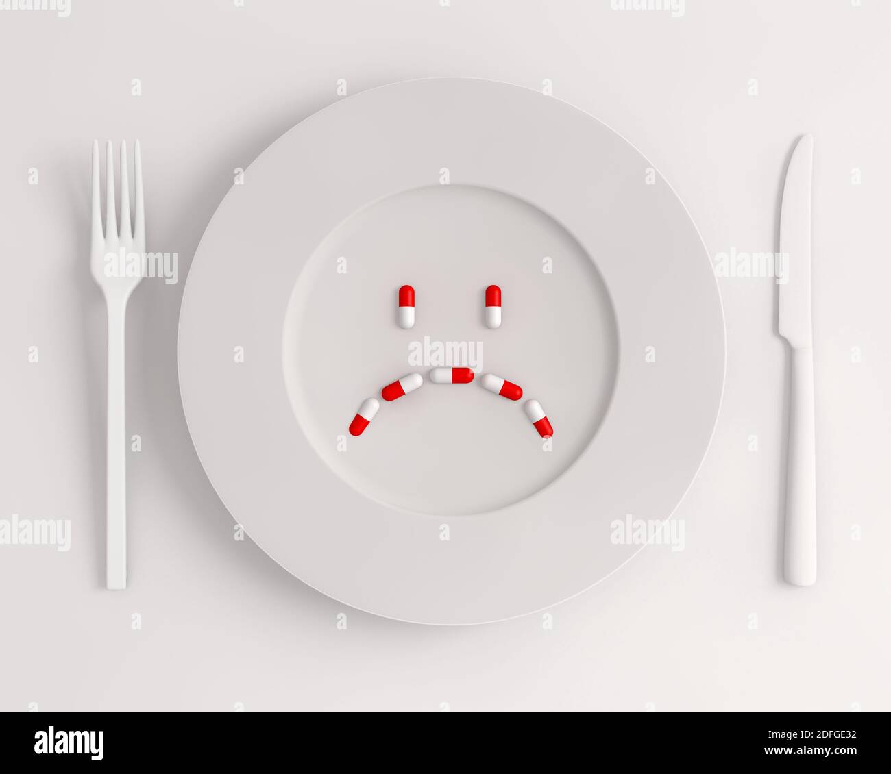 a top view white plate with pills forming a sad face fork and knife on ...