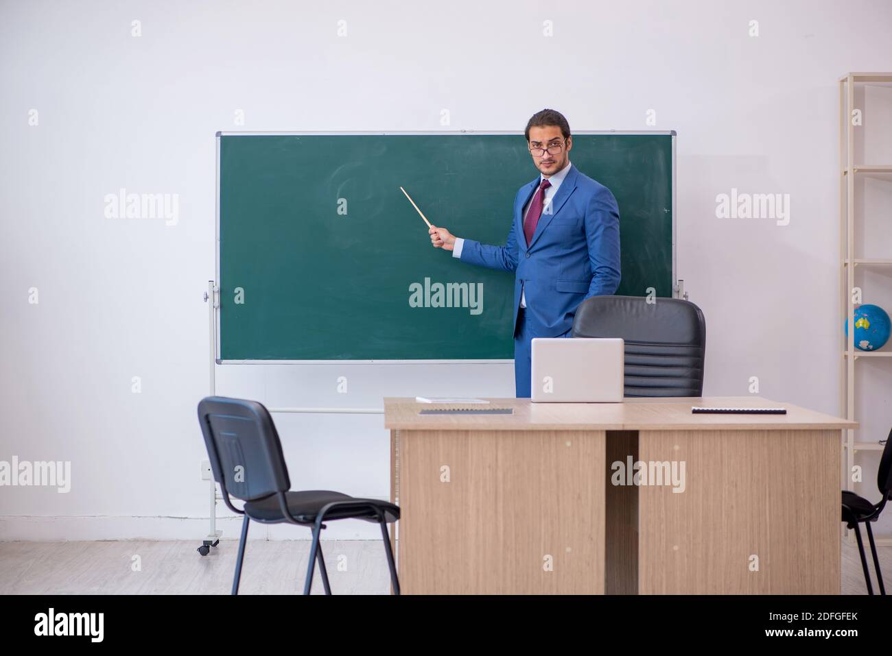 Young teacher in suit in front of green board Stock Photo - Alamy