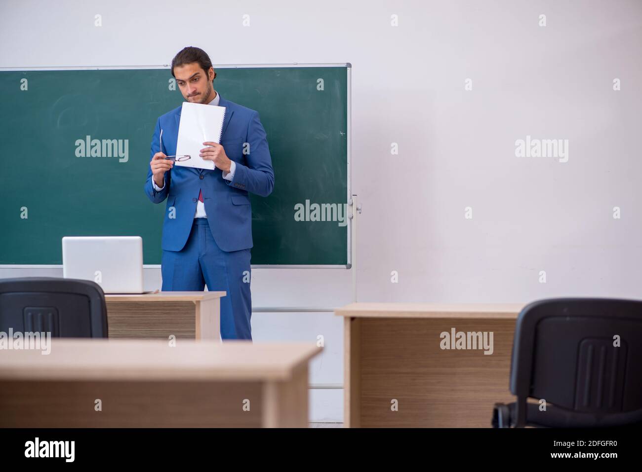 Young teacher in suit in front of green board Stock Photo - Alamy