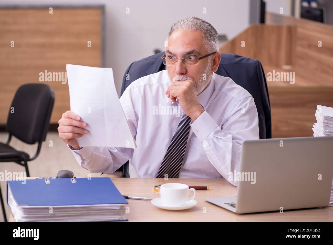 Old employee reading paper in the office Stock Photo - Alamy