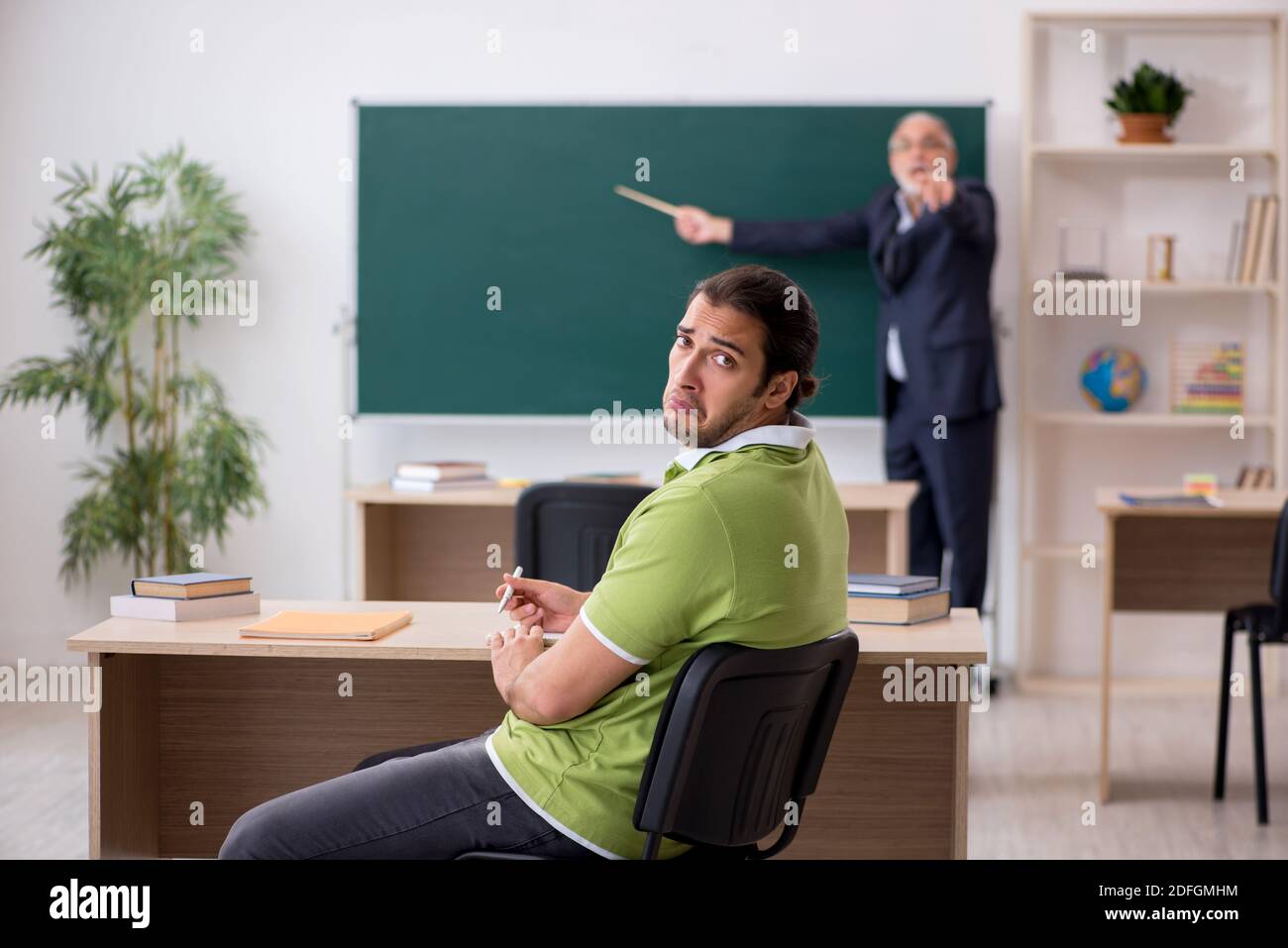Aged male teacher and lazy student in the classroom Stock Photo - Alamy
