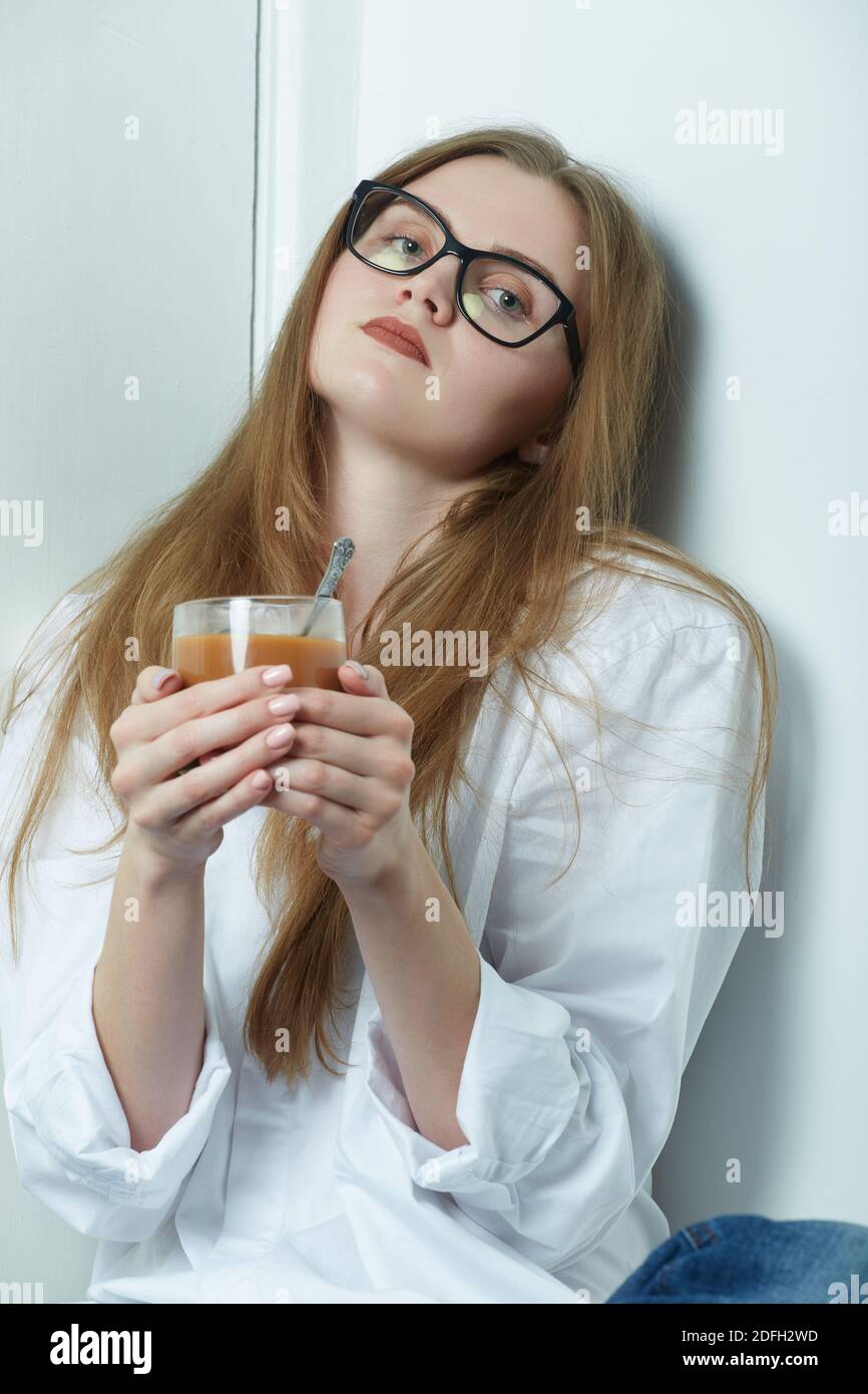 Sad Young Woman In Eyeglasses Sitting In Corner Looking At Camera Stock