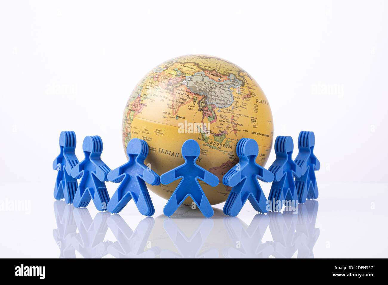 A closeup of the paper man holding hands around the planet earth globe ...