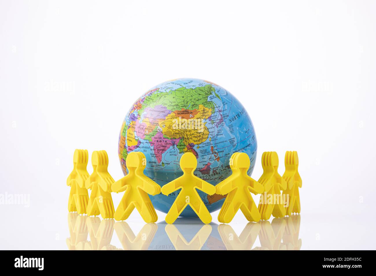 A closeup of the paper man holding hands around the planet earth globe ...