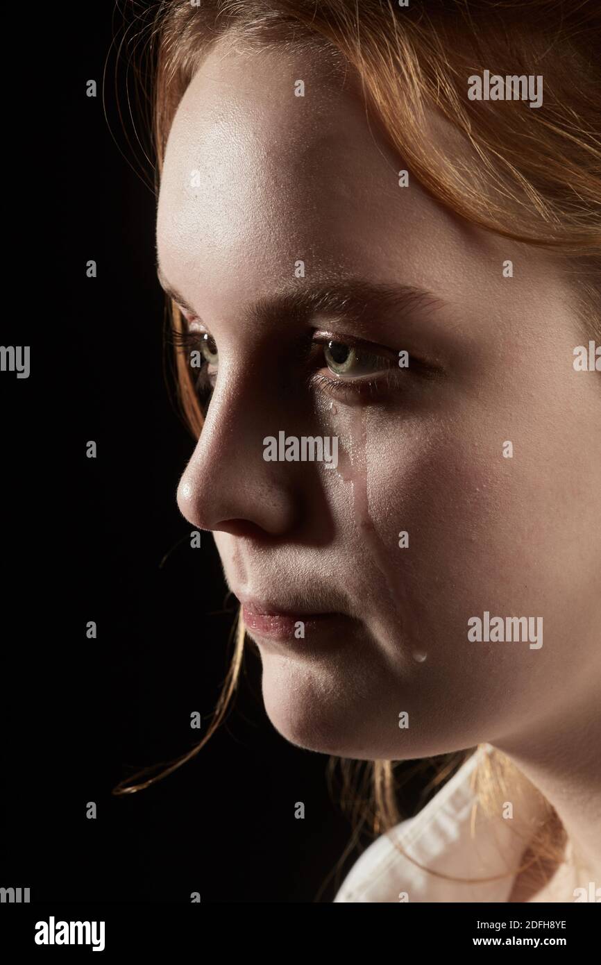 sad woman crying, looking aside on black background, closeup portrait ...