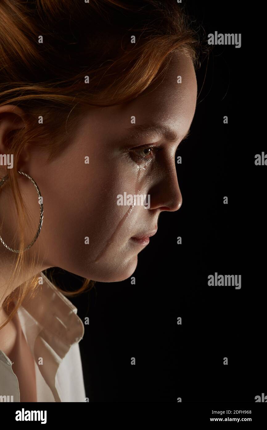sad woman crying, looking aside on black background, closeup portrait ...
