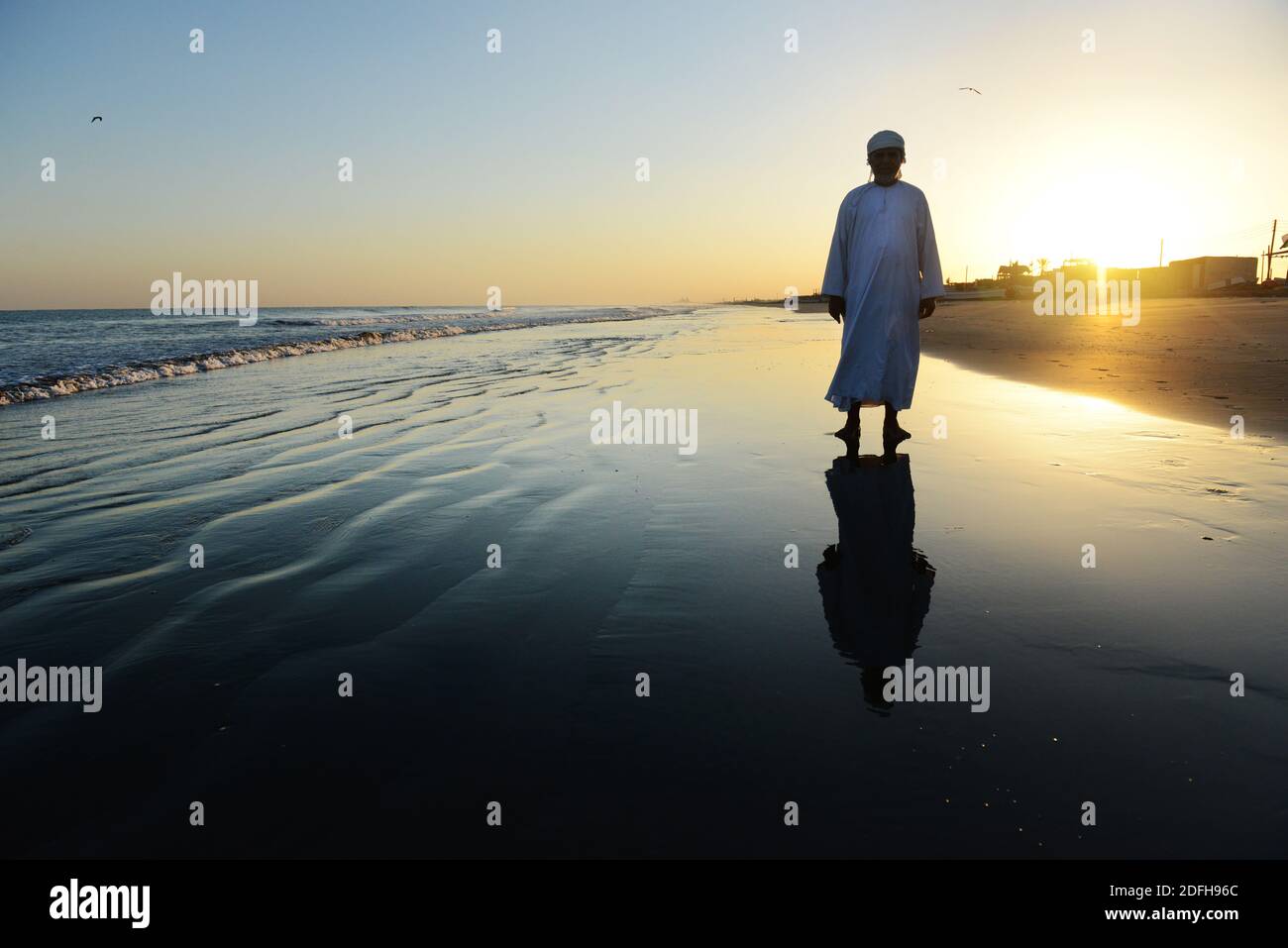 An Omani man walking on th Barka beach in Oman Stock Photo - Alamy