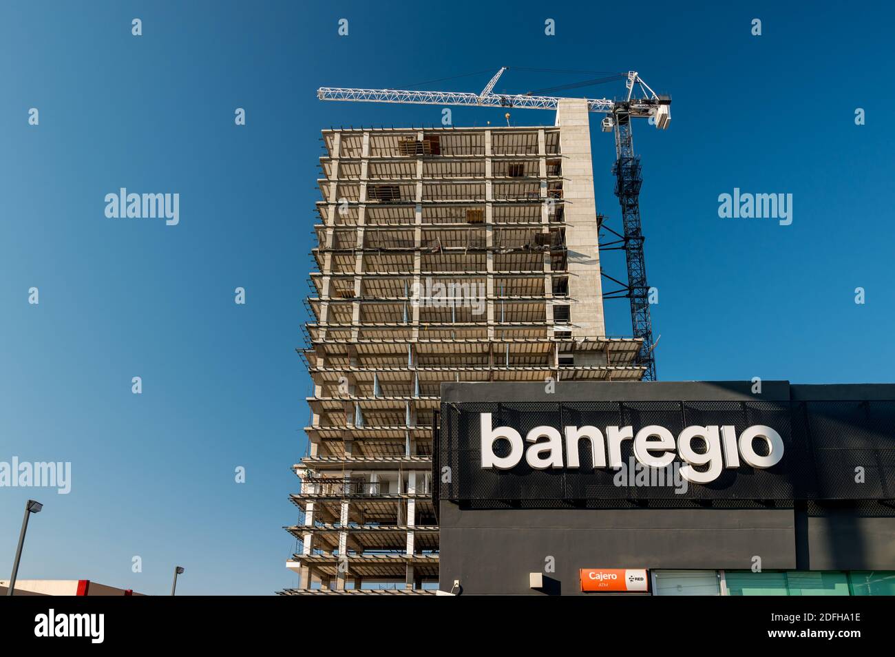 New construction high-rise building with crane in front of a Banregio ...