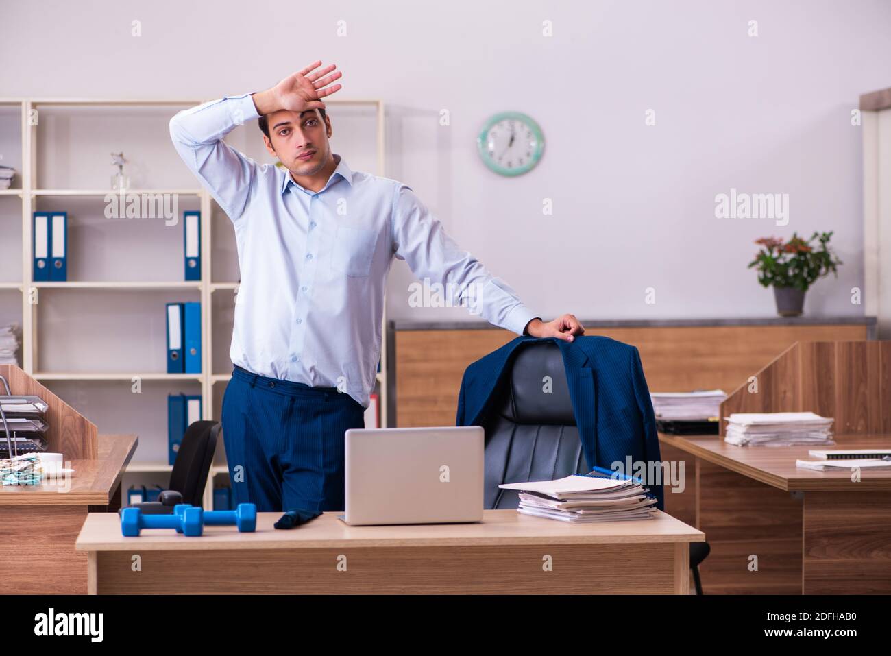 Young employee doing physical exercises at workplace Stock Photo - Alamy