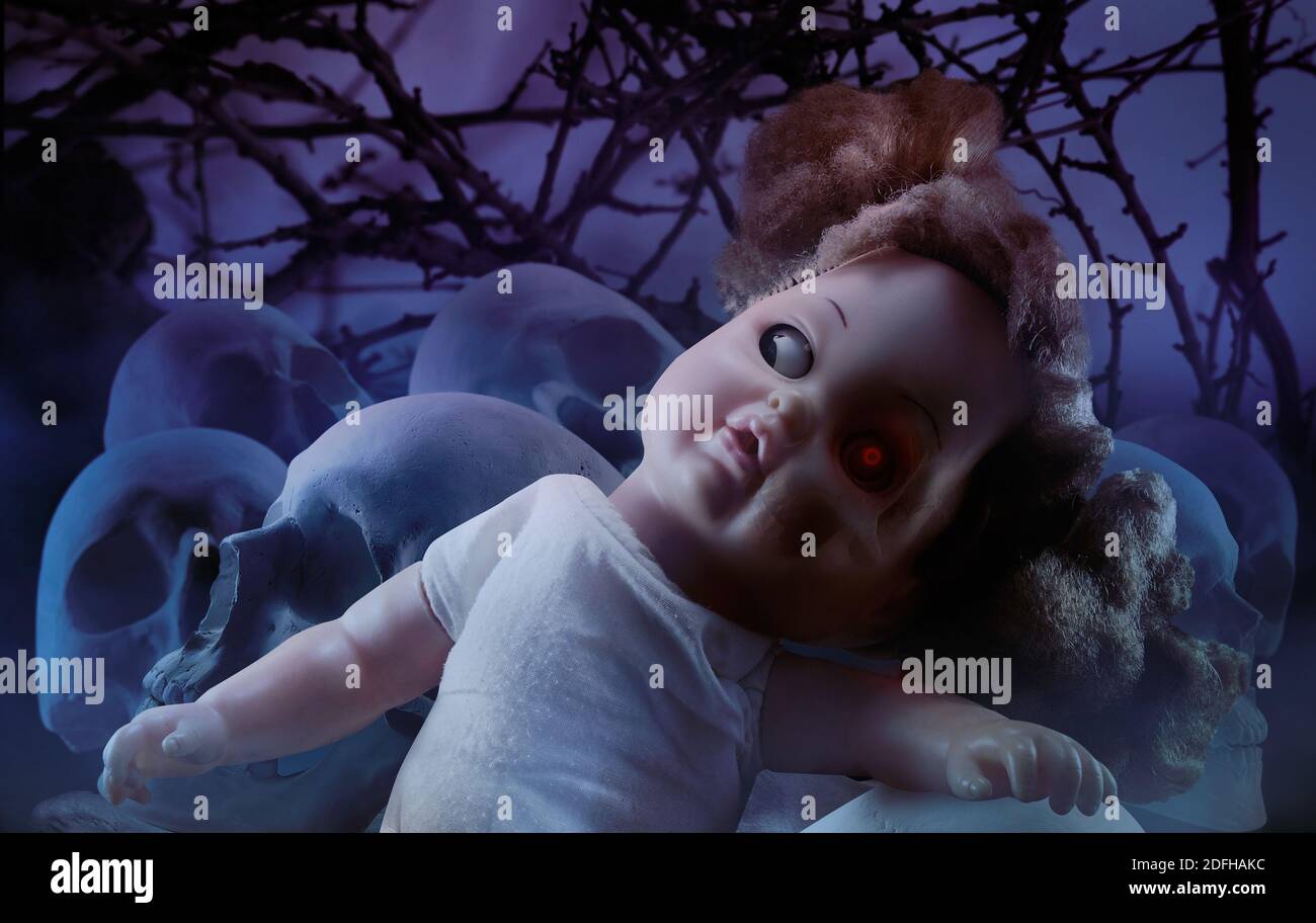 Scary horror plastic doll with red eye laying on human skulls on ...