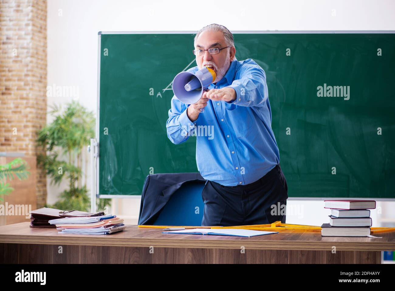 Angry male math teacher holding megaphone Stock Photo - Alamy