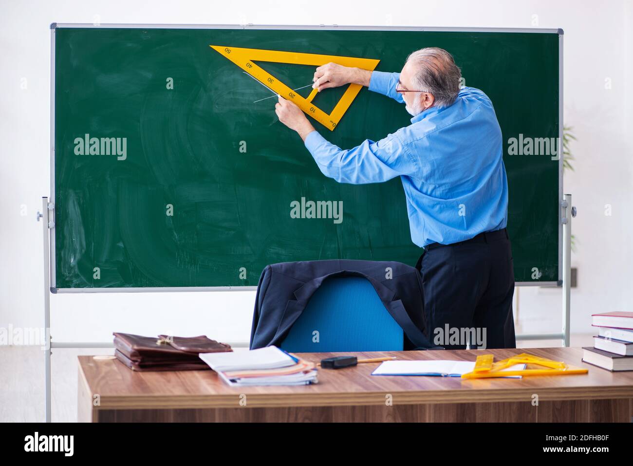 Senior male geometry teacher holding triangle Stock Photo - Alamy