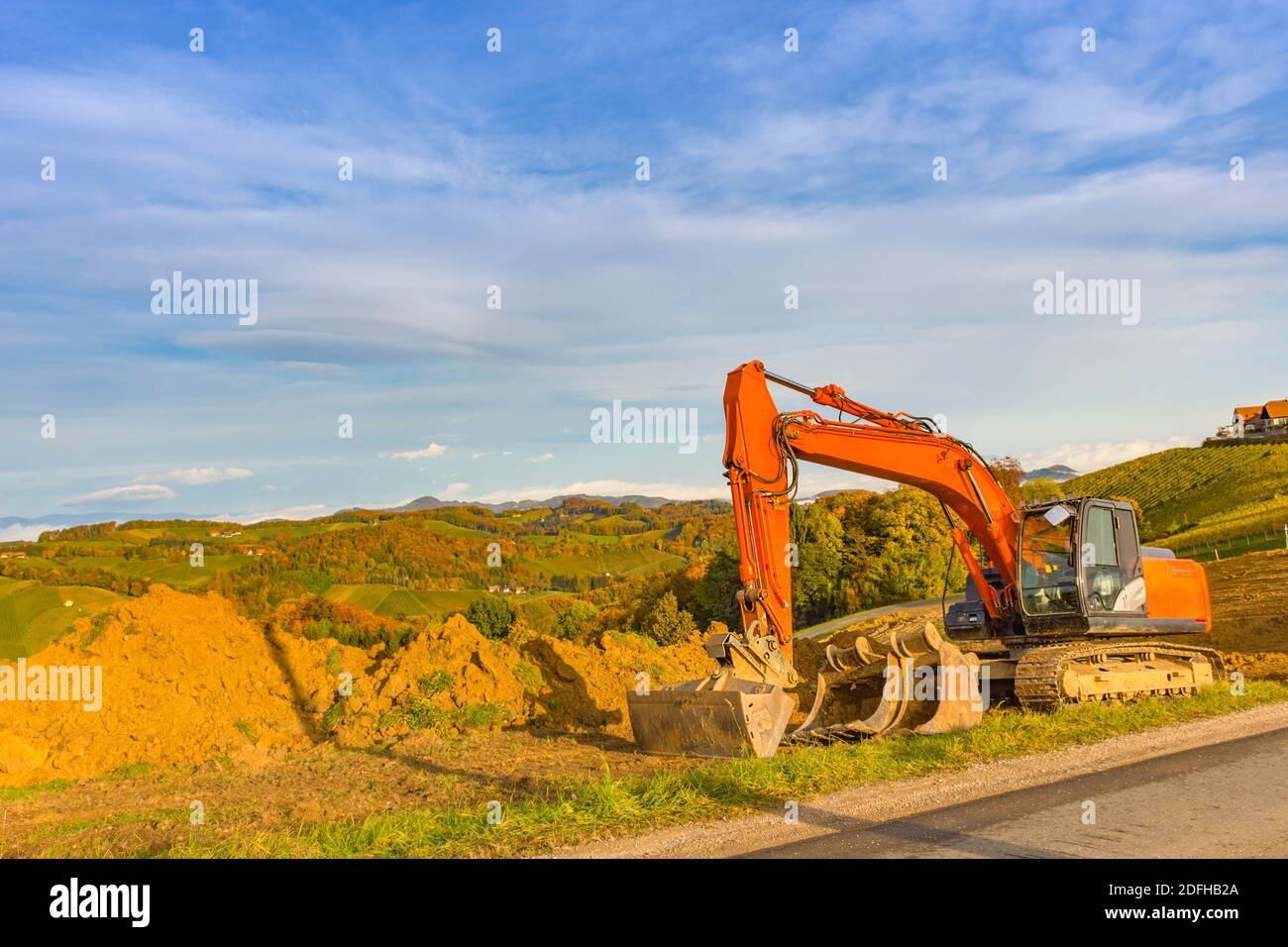 Orange digger/excavator machine excavating the vineyards farmland for ...