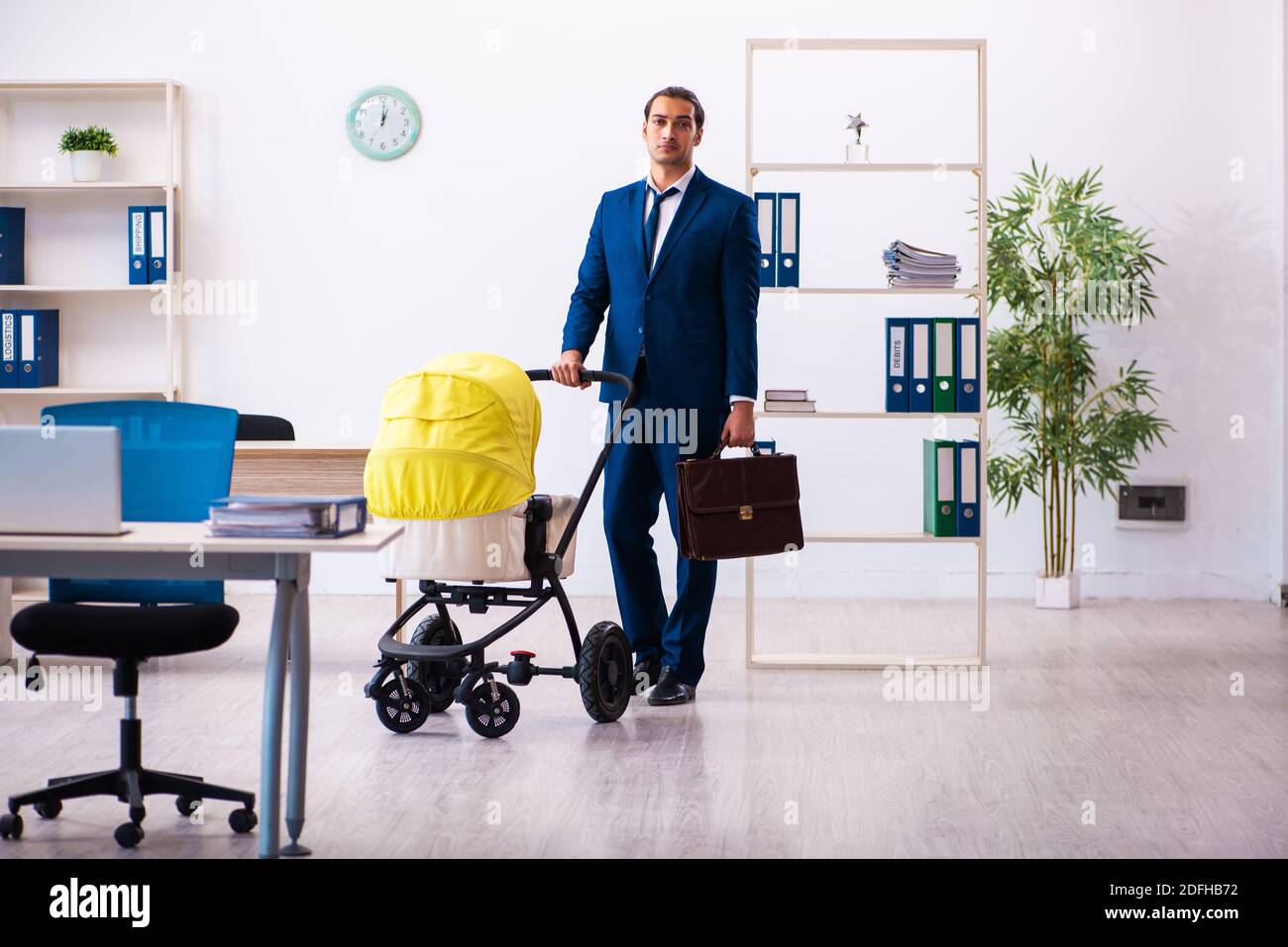 Young employee looking after kid at workplace Stock Photo - Alamy