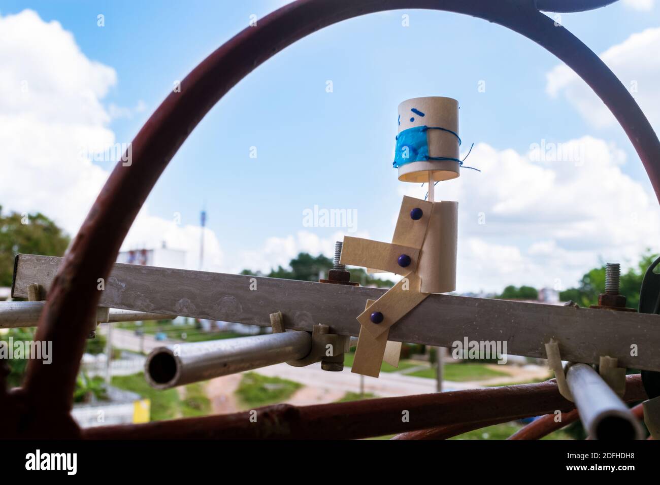 Cardboard dummy wearing a mask sitting on a tv antenna looking outside ...