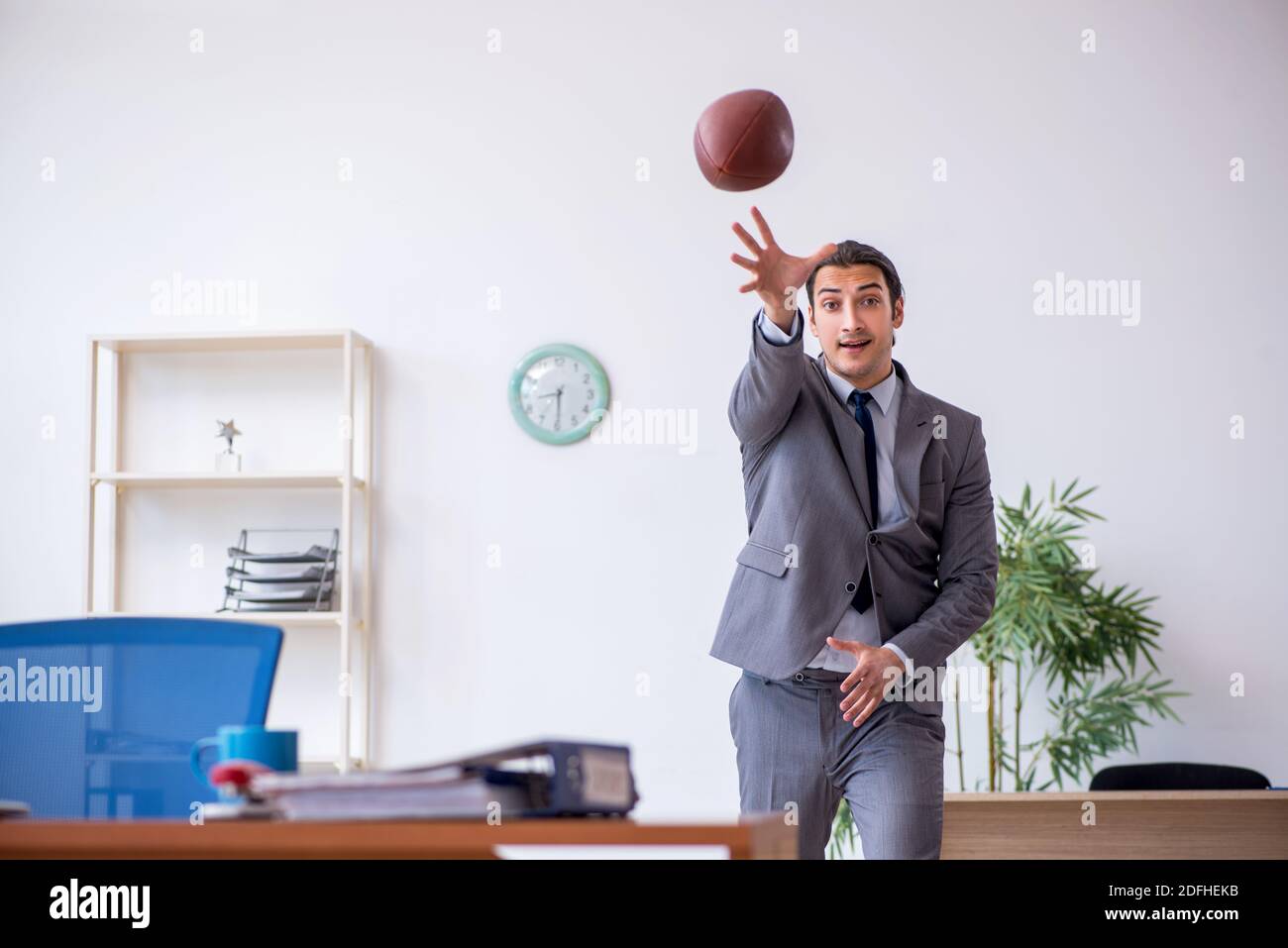 Male employee with rugby ball in the office Stock Photo - Alamy