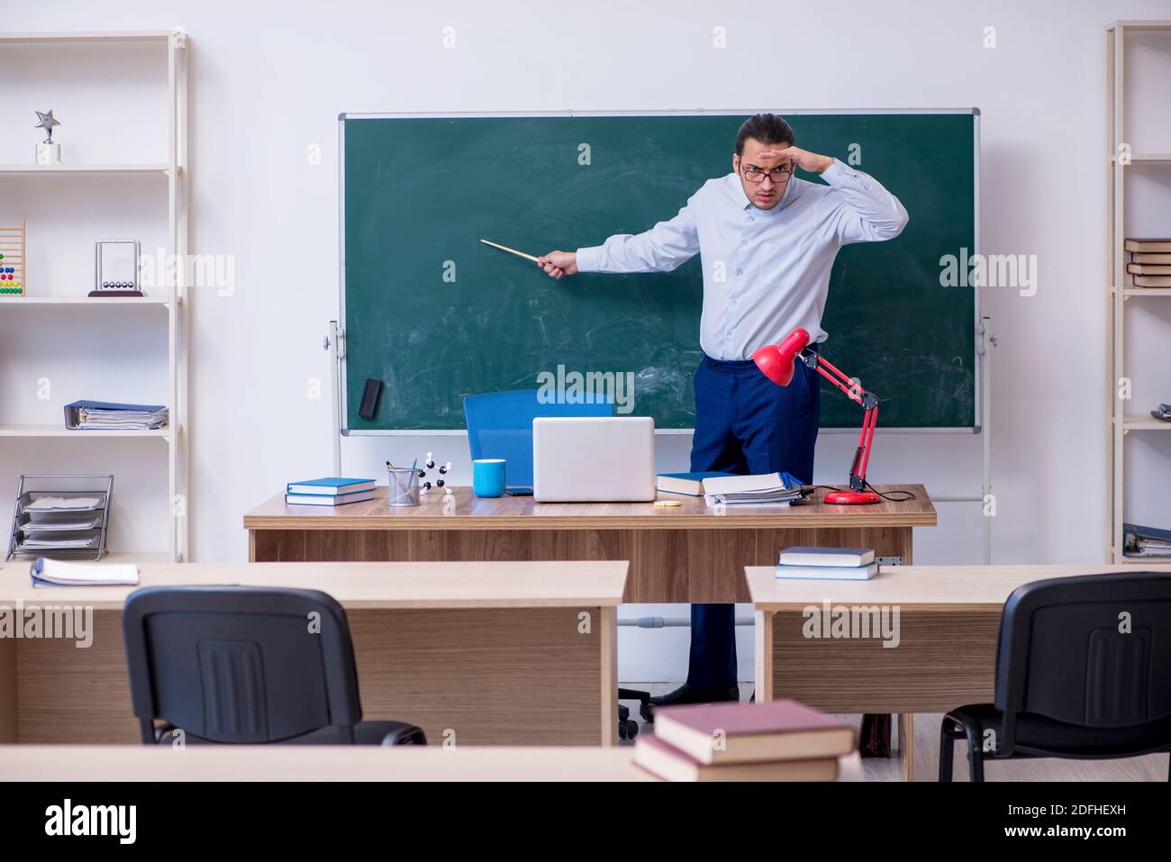 Young teacher in front of green board Stock Photo - Alamy