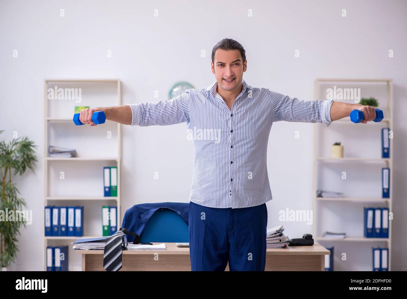 Handsome male employee doing exercises in the office Stock Photo - Alamy
