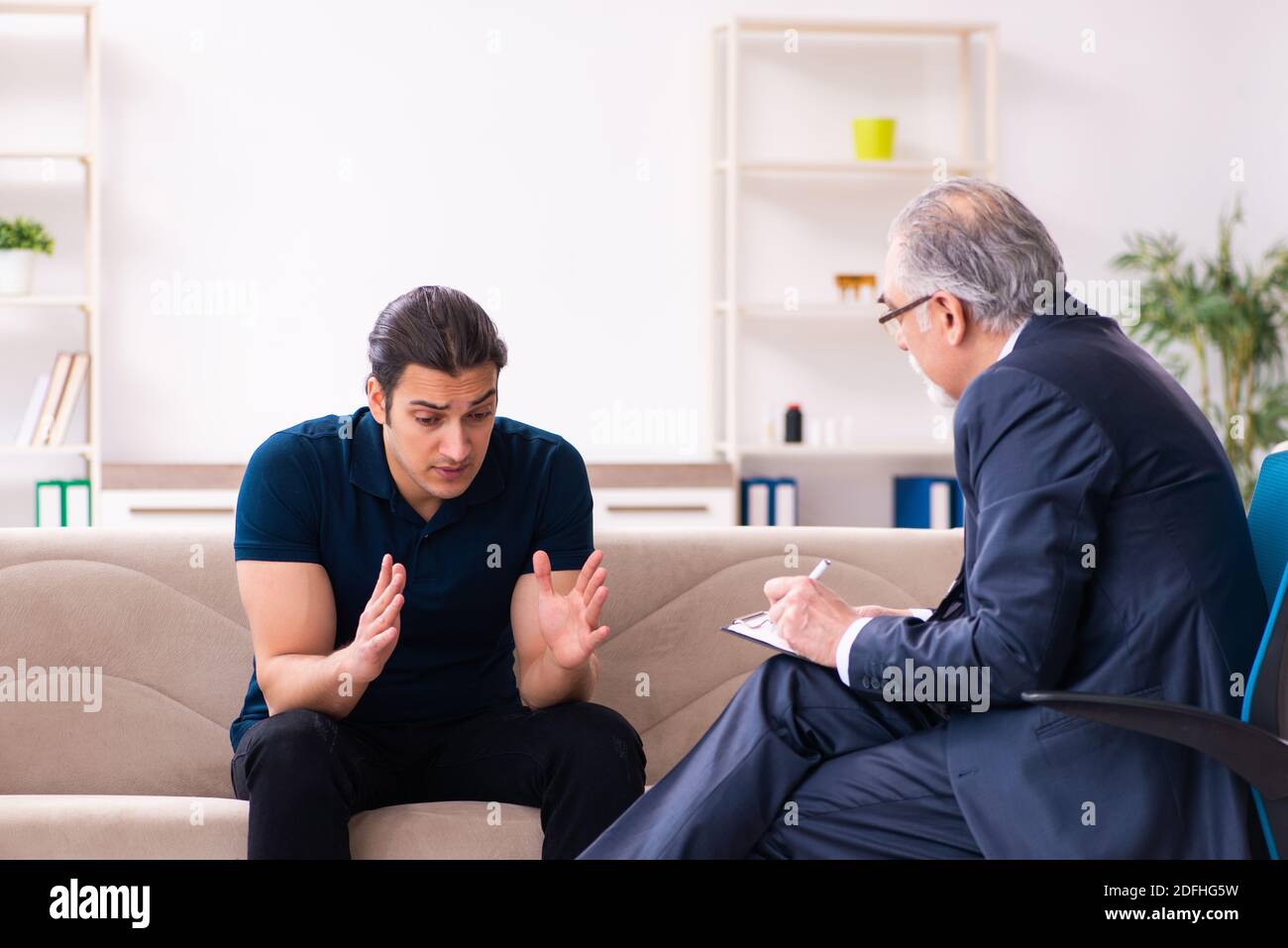Young man visiting old psychologist Stock Photo - Alamy
