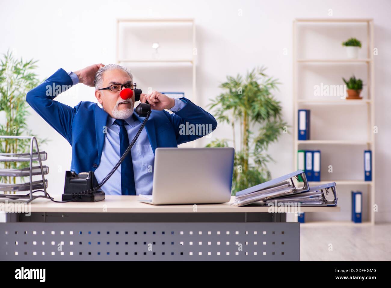 Aged businessman clown working in the office Stock Photo - Alamy