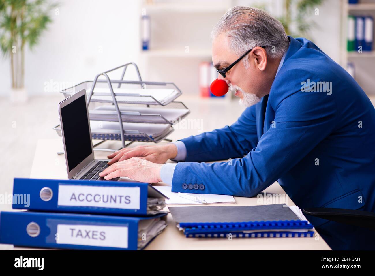 Aged businessman clown working in the office Stock Photo - Alamy