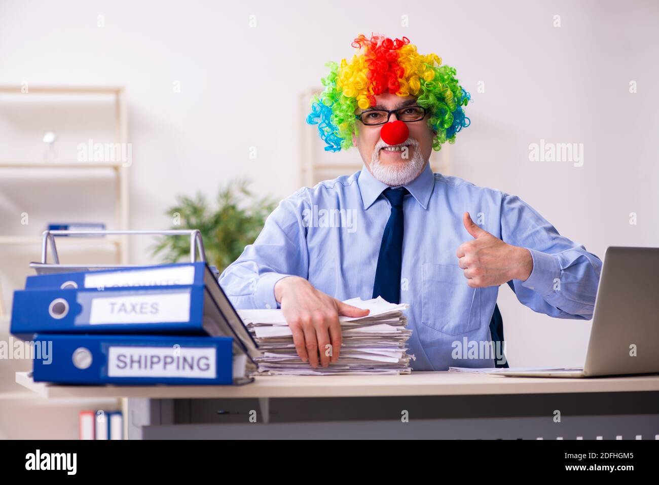 Aged businessman clown working in the office Stock Photo - Alamy