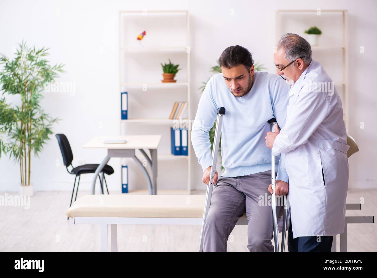 Leg injured man visiting old doctor osteopath Stock Photo - Alamy