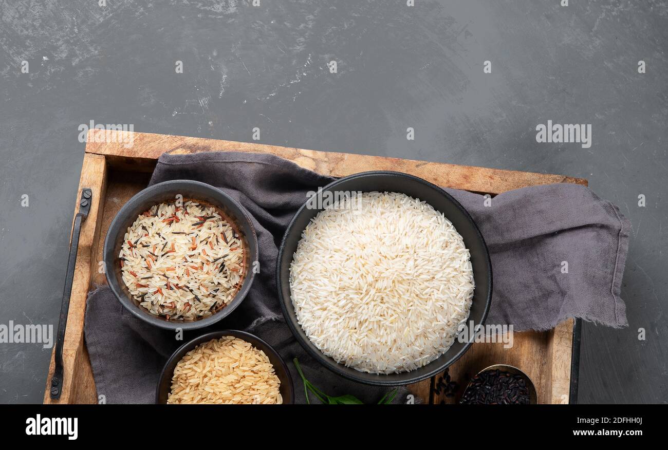 Set with different types of rice on grey background, top view with copy ...