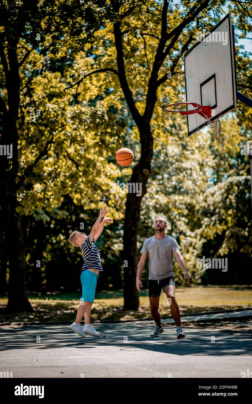 Cute blond boy practicing basketball with his coach Stock Photo - Alamy